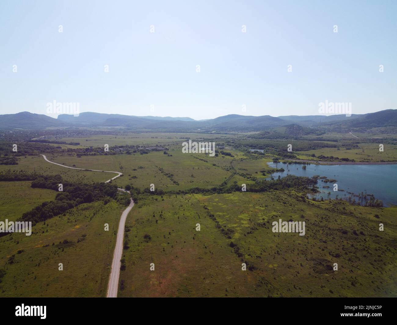 Luftaufnahme des Wasserreservoirs im Bergtal, das mit einem grünen ...