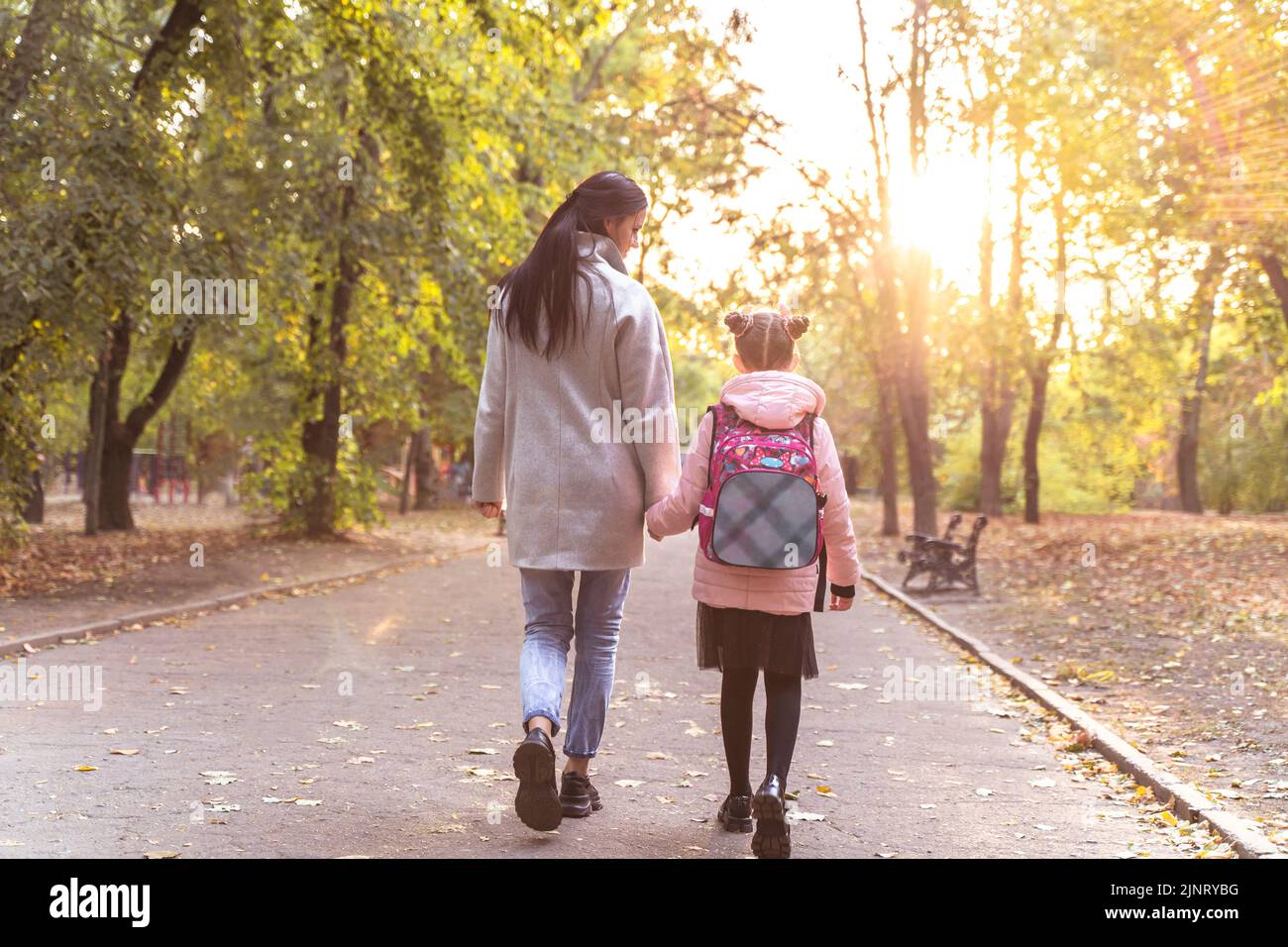 Mutter und Tochter gehen im Herbstpark spazieren. Kleines Mädchen nach der Schule mit Mutter von ...