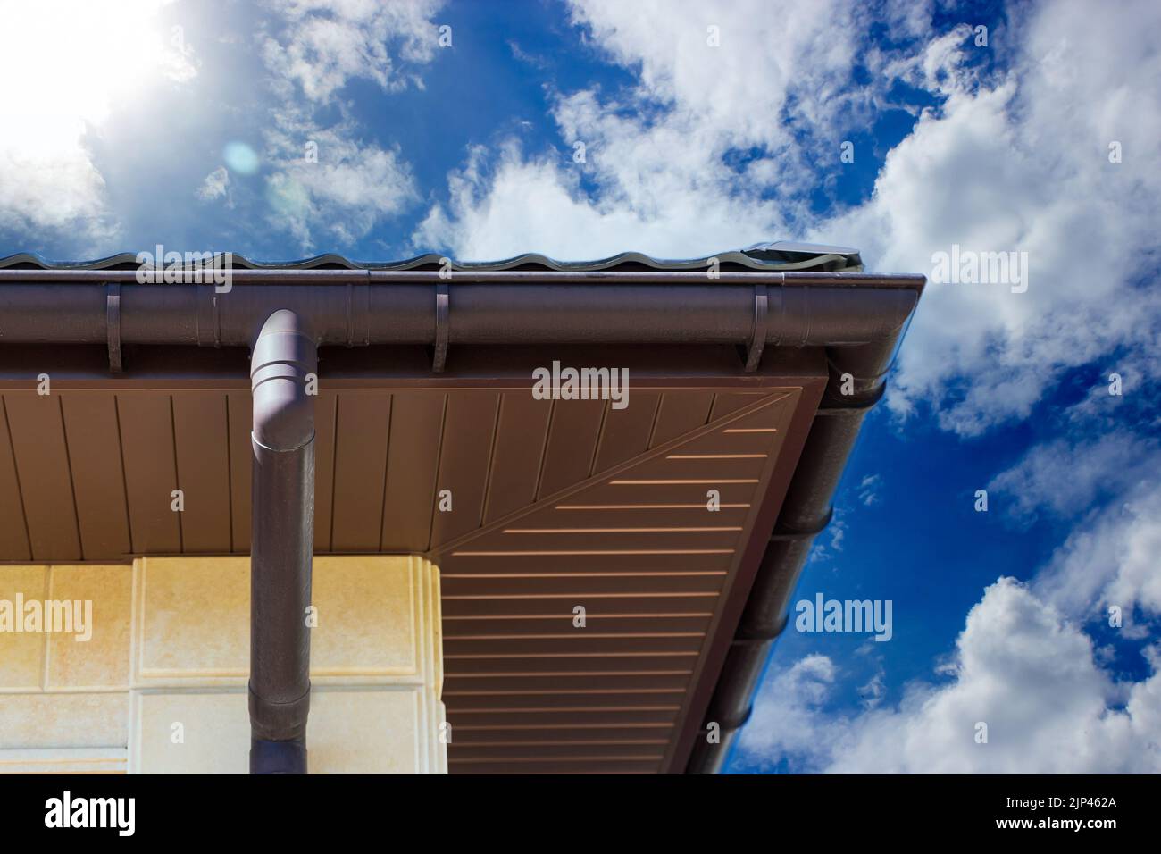 Dachrinnenrohrsystem an der Ecke des Hauses. Regenrinne mit Halterungen und Fallrohr gegen den ...