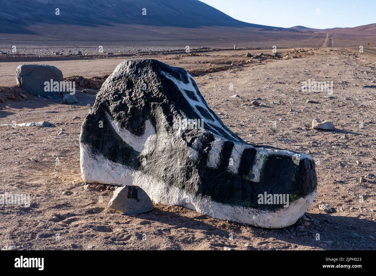 Ein großer Fels, der als Sportschuh gemalt ist, entlang einer Straße ...