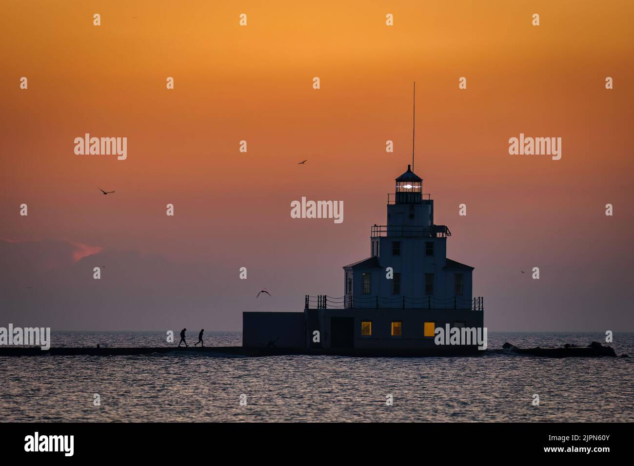 Zwei Personen bei einem Spaziergang bei Sonnenaufgang zum Leuchtturm am Lake Michigan in ...