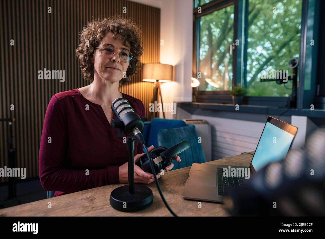 Der reife Moderator trägt eine Brille mit einem Headset, das mit einem ...