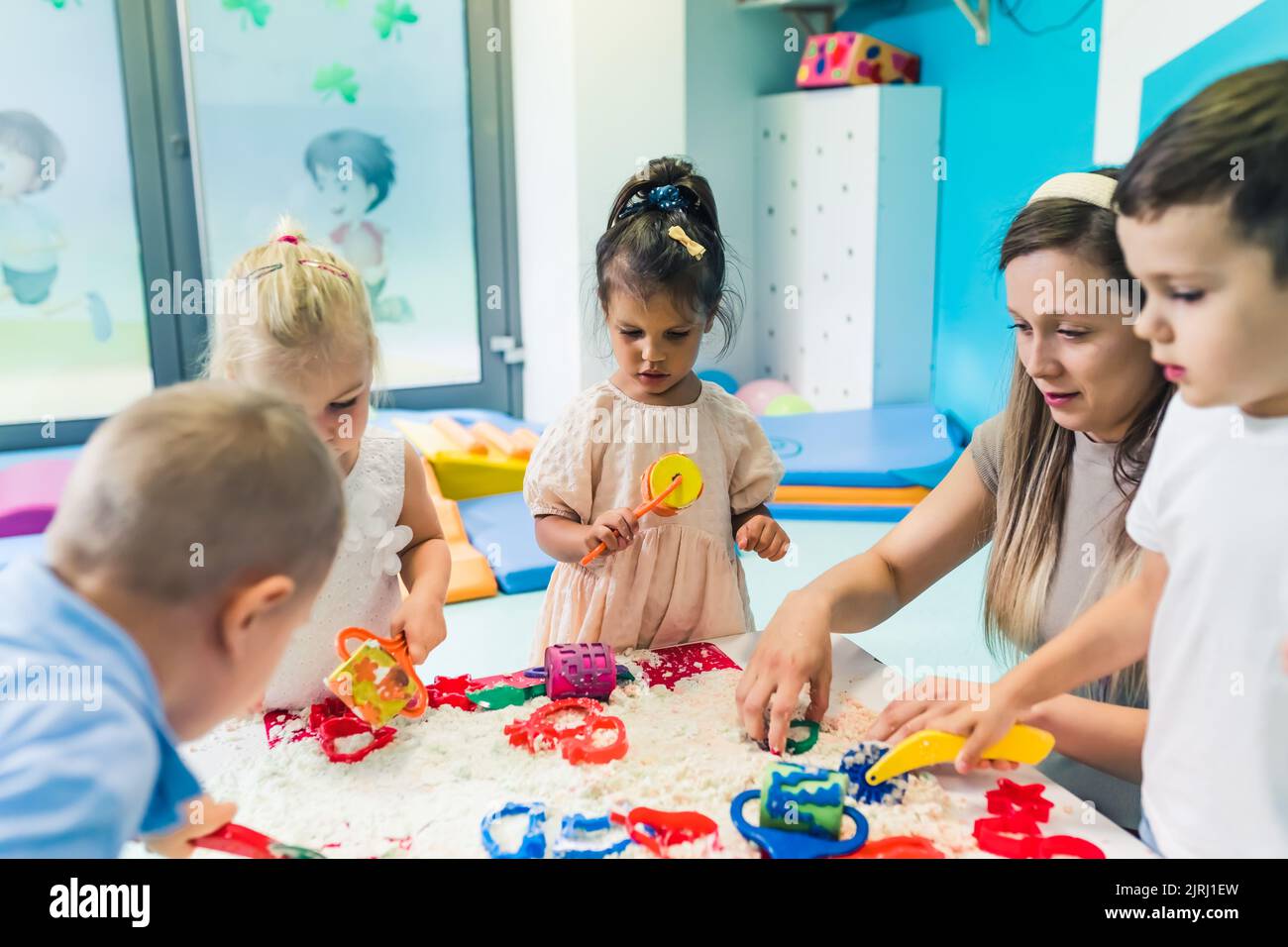 Sensorisches Spielen in der Kinderschule. Kleinkinder mit ihrem Lehrer ...