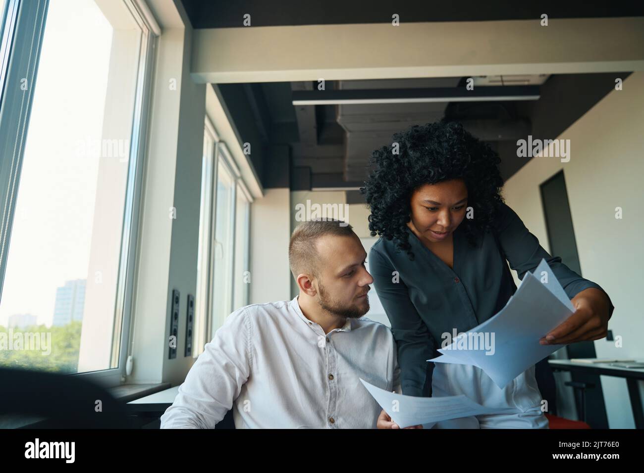 Hübsche Managerin im Büro, die Dokumente von Kollegen zeigt ...