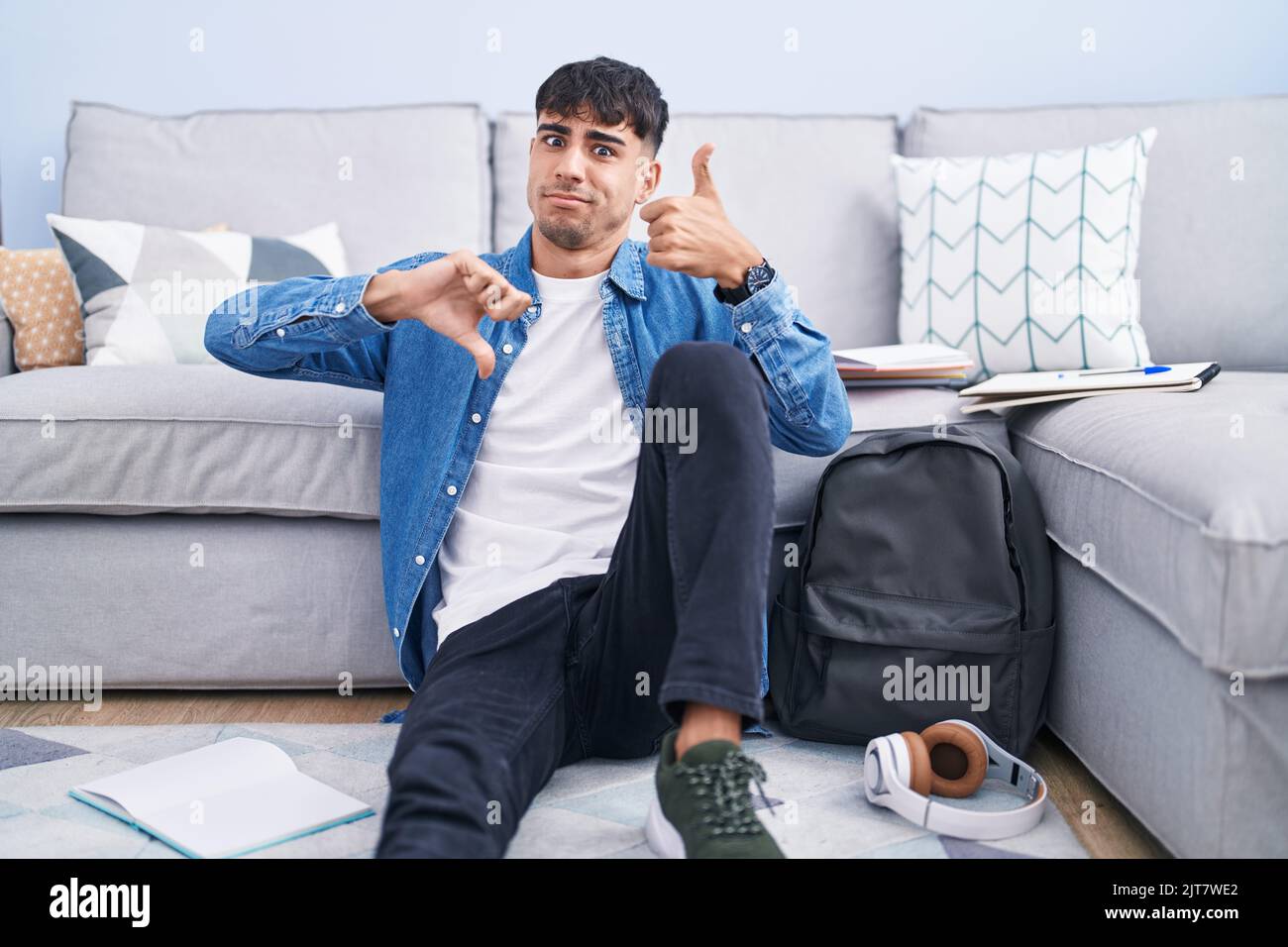 Junger hispanischer Mann, der auf dem Boden sitzt und für eine ...