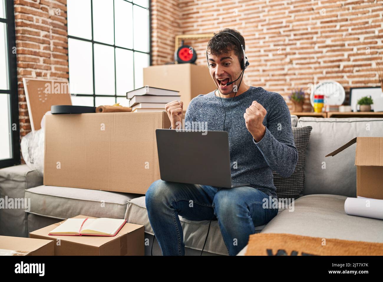 Der junge hispanische Mann, der mit einem Laptop zu Hause arbeitet ...