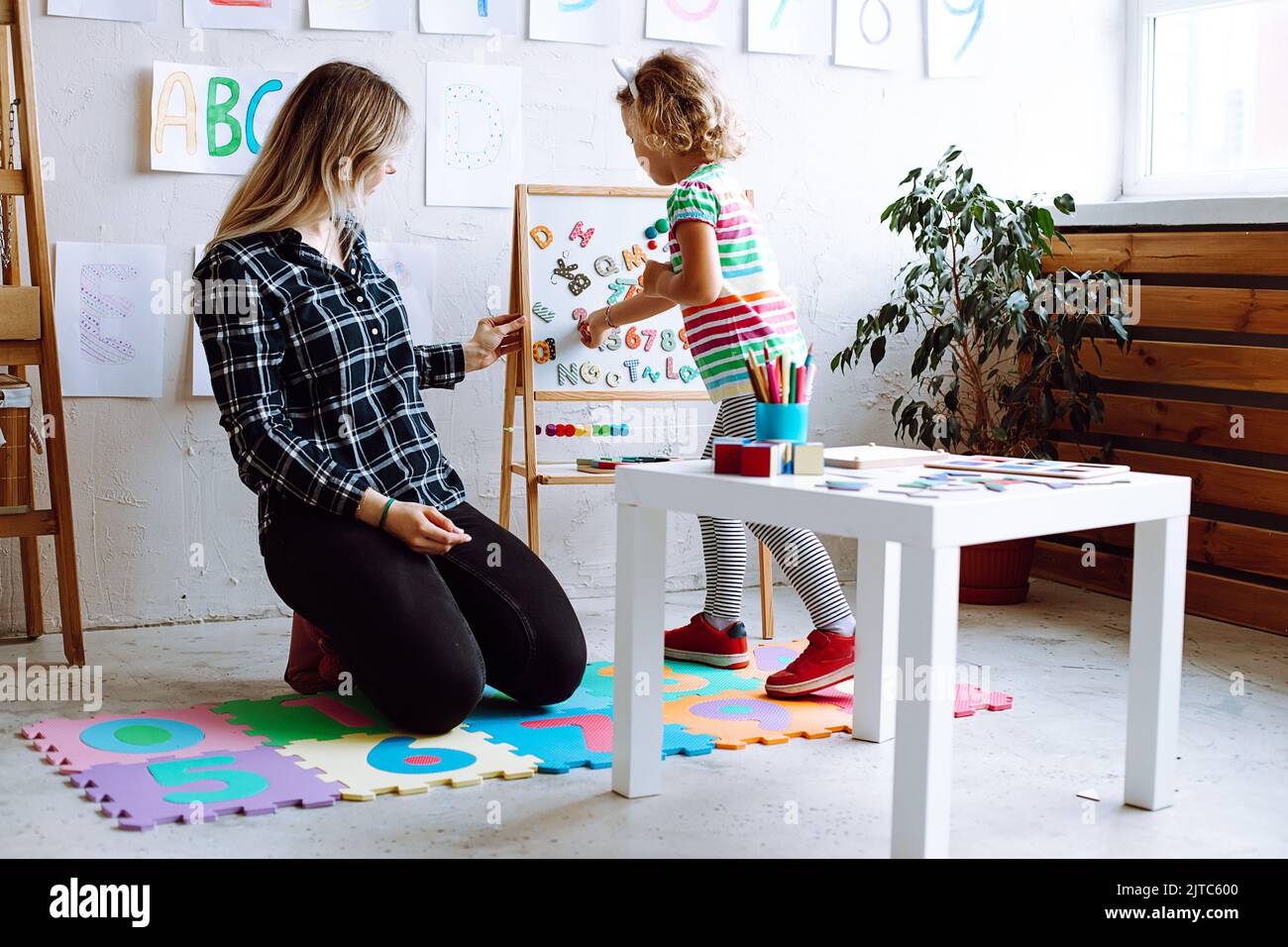 Lehrer und Mädchen machen Übung auf Magnetbrett. Kind lernt englisch ...