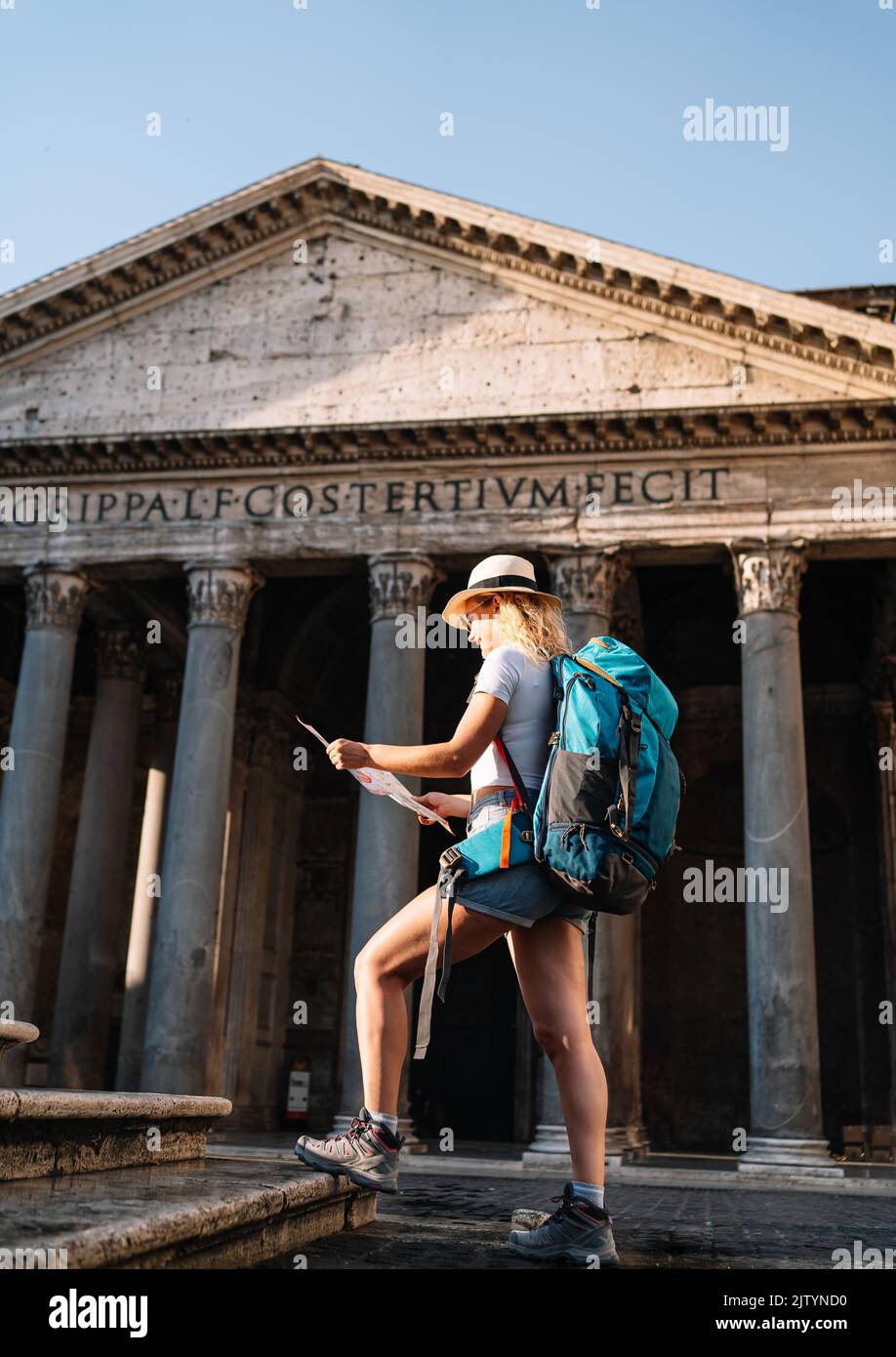 Die vertikale Aufnahme von Young Woman hält ihre Karte von Rom, um die ...