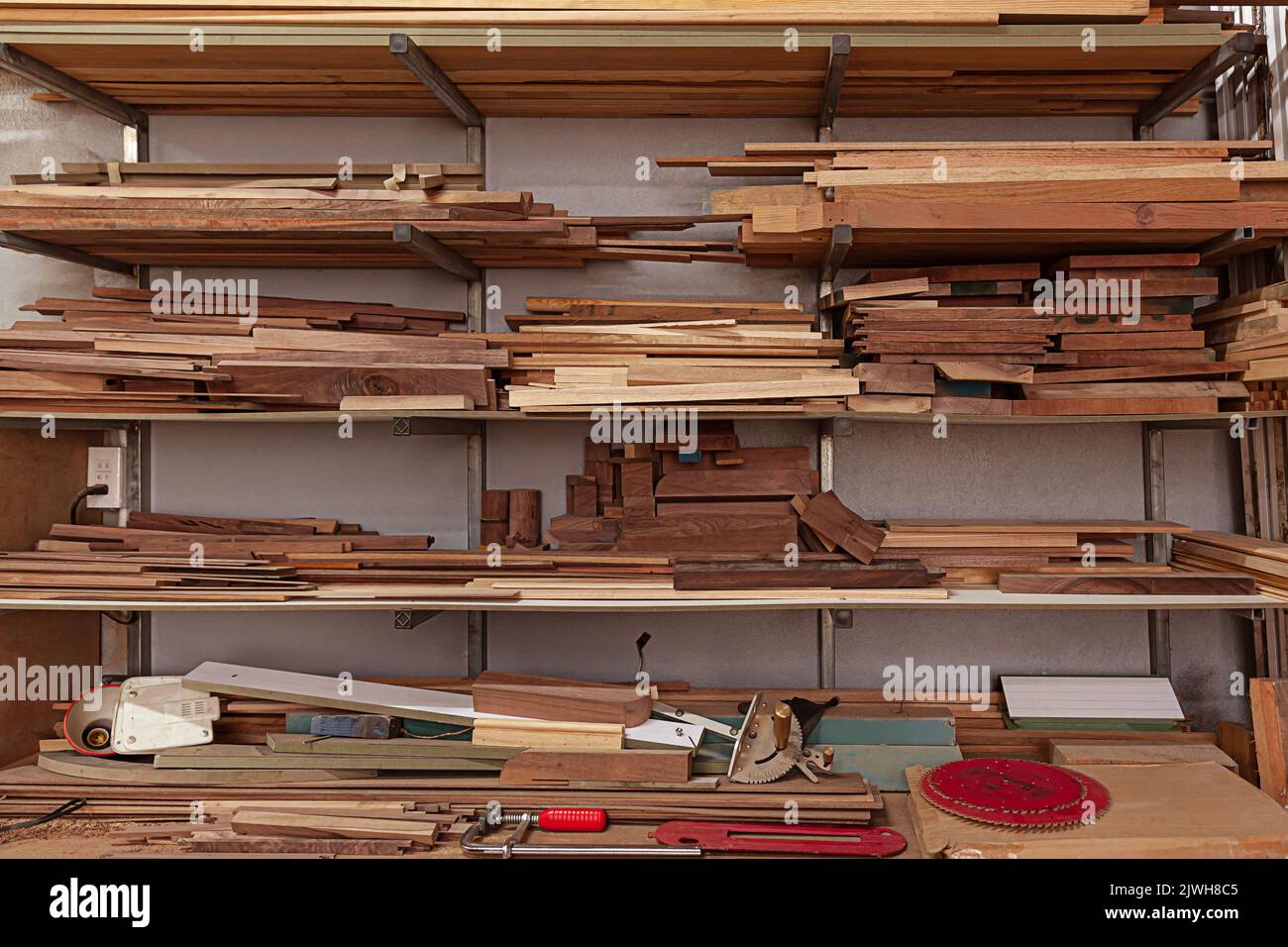 Holzwerkstatt mit Regalen, die Holzteile, Bretter an der Wand und einige Handwerkzeuge auf dem ...