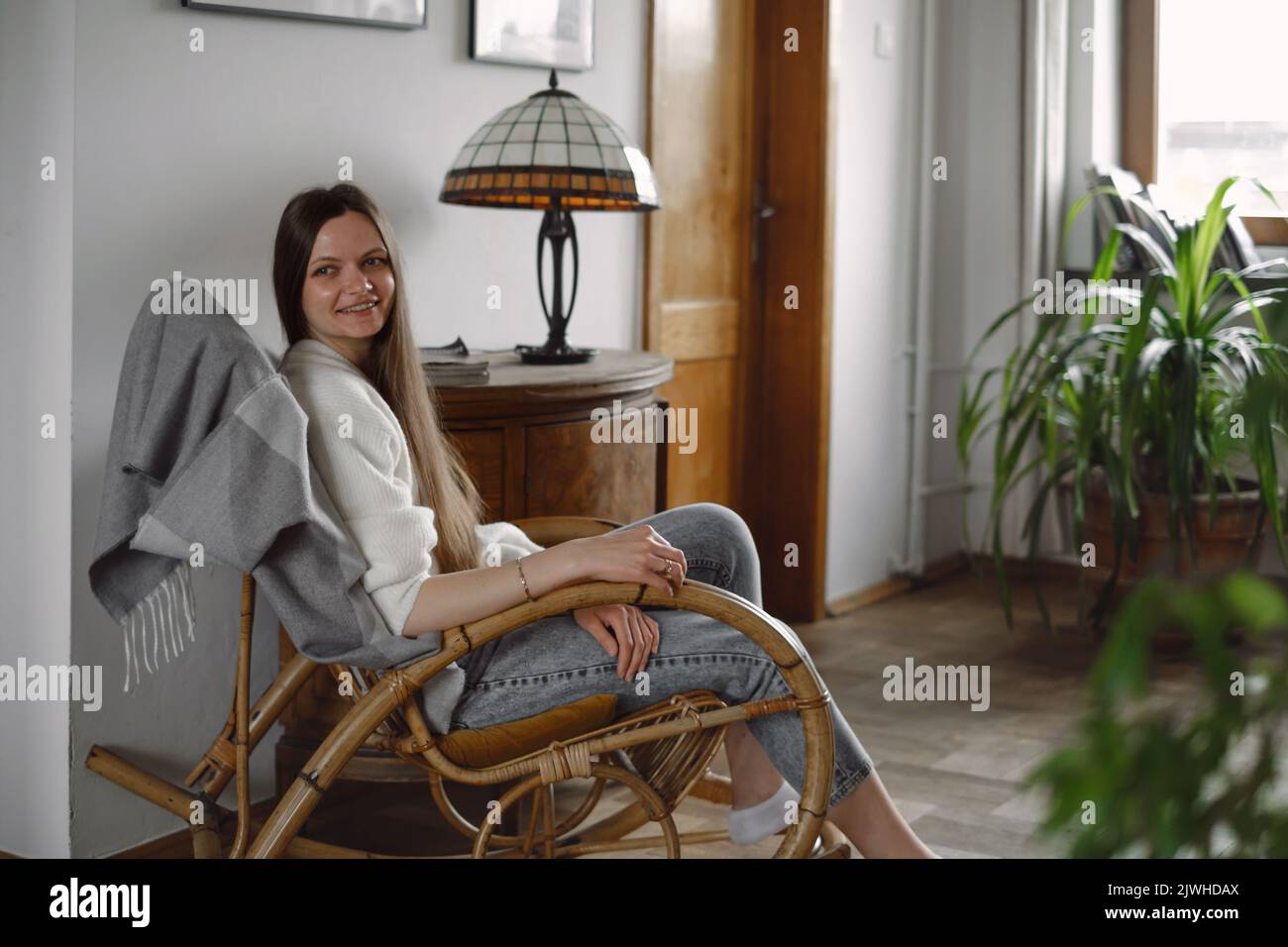 Junge Frau, die auf einem Schaukelstuhl sitzt. Gemütliche Atmosphäre ...