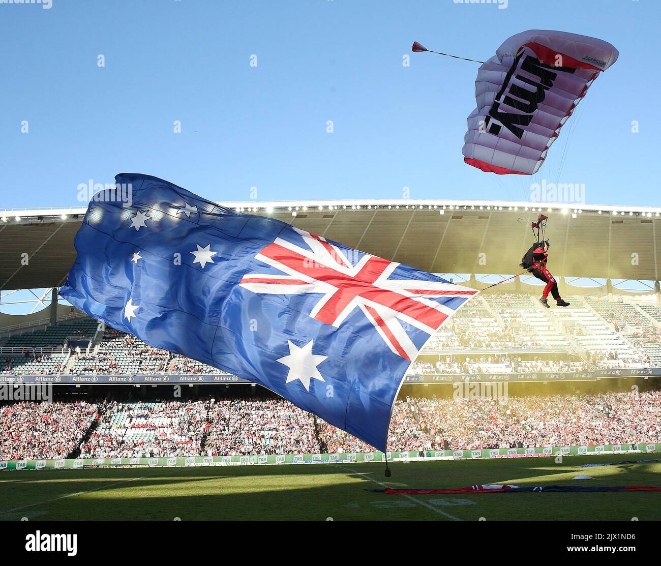 Ein Fallschirmspringer landet auf dem Spielfeld mit der australischen Flagge während eines Anzac ...
