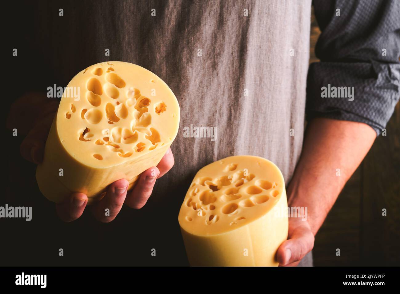 Menschenhände halten zwei große Scheiben Käse maasdam vor dem ...