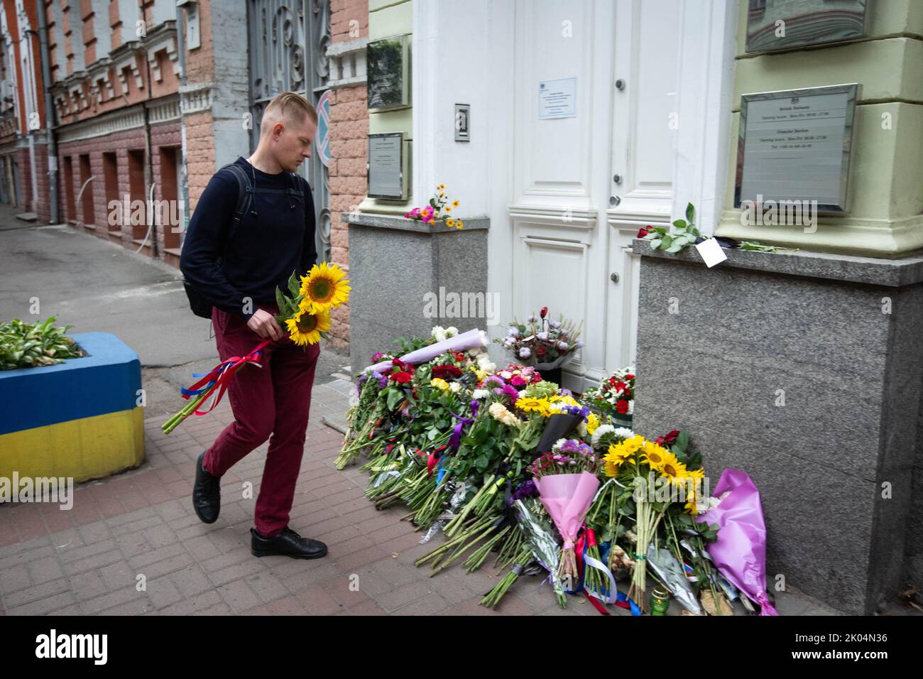 Ein Mann stellt Blumen zur Hommage an Königin Elizabeth II. Vor der ...