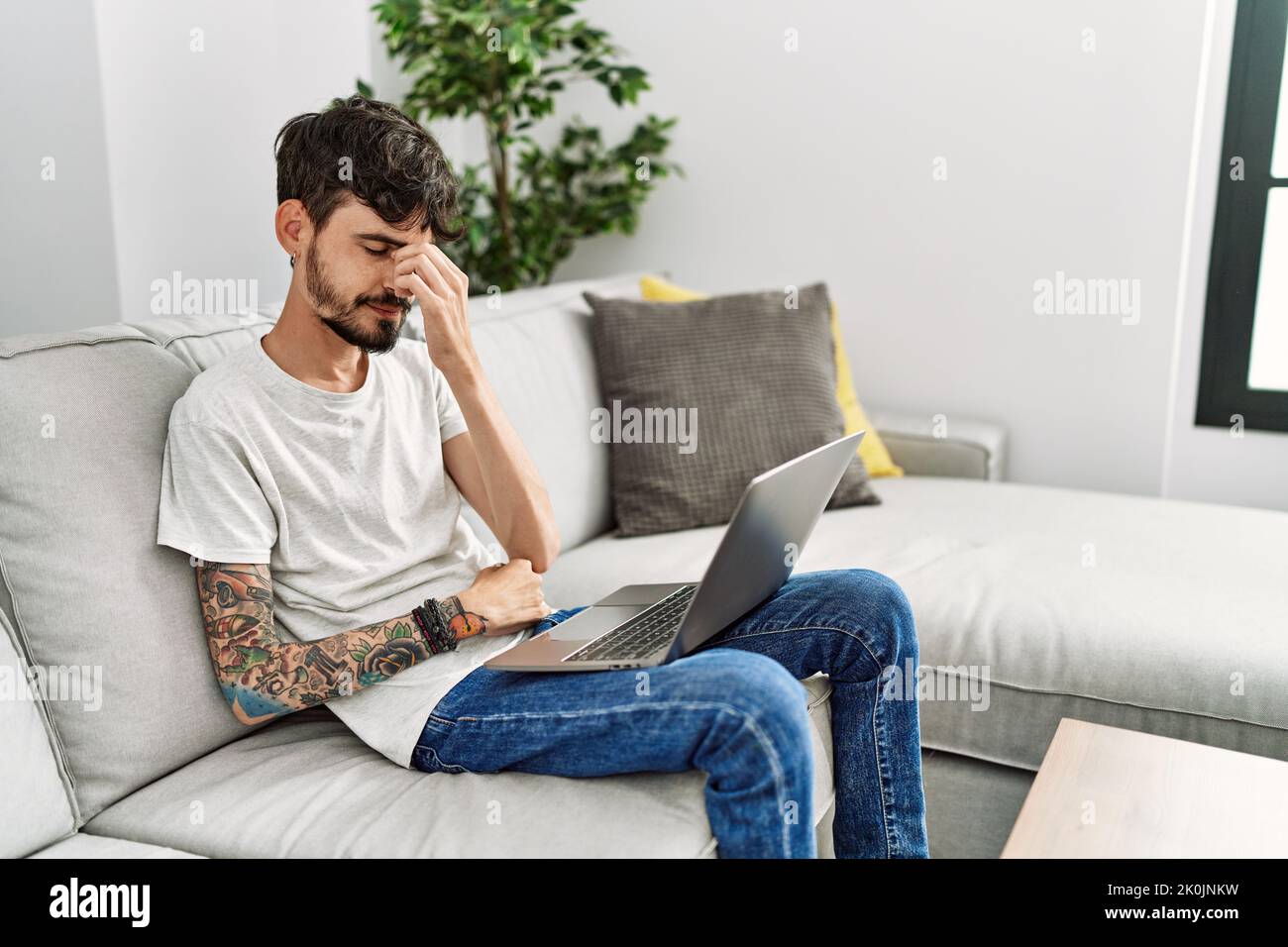 Hispanic Mann mit Bart sitzt auf dem Sofa müde reiben Nase und Augen ...