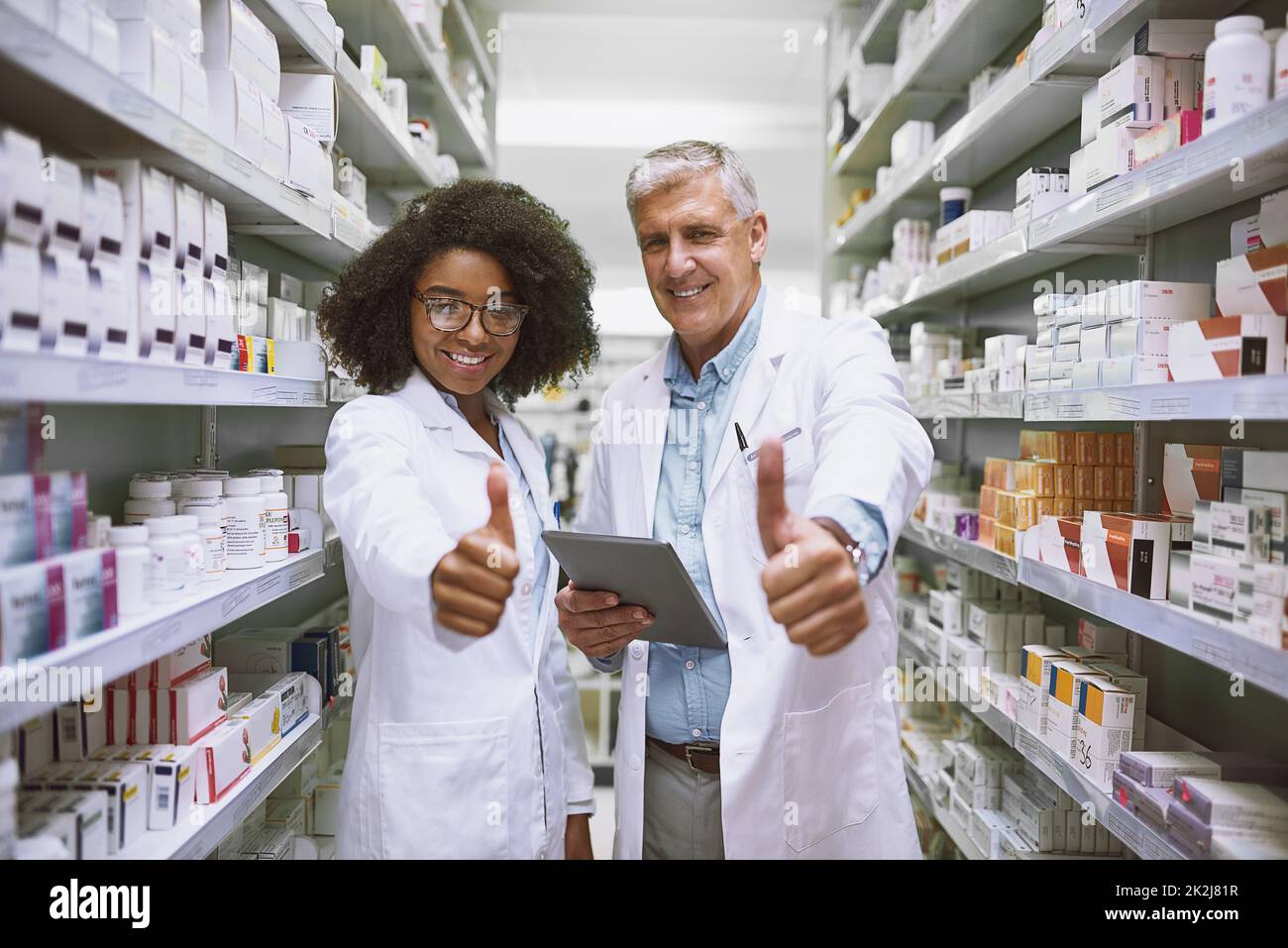 Wir sind auf Kurs mit dem Lager. Porträt zweier fröhlicher Apotheker, die ein digitales Tablet ...