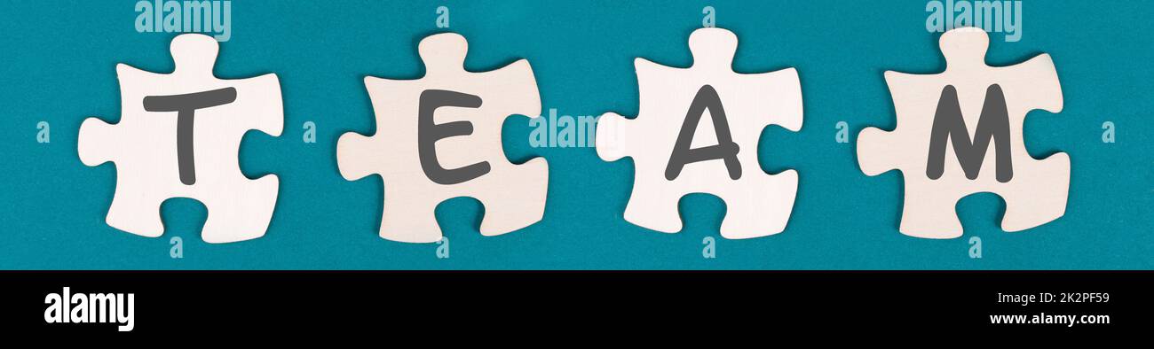 Das Wort-Team steht auf Puzzleteilen, verbindet die Teile miteinander ...