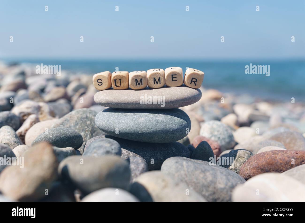 An einem Steinstrand, eine Pyramide aus Steinen, auf denen Holzwürfel ...
