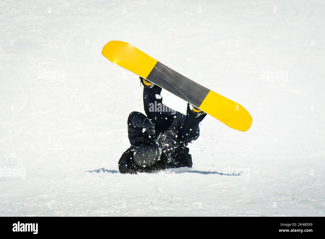 Der männliche Snowboarder auf dem Snowboard landet auf dem Rücken im ... Der männliche Snowboarder auf dem Snowboard landet auf dem Rücken im ...