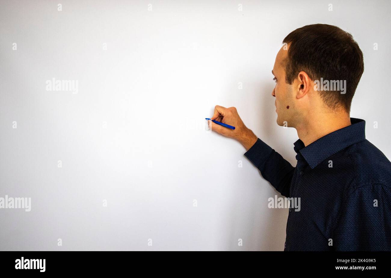 Ein hübscher Mann steht an der weißen Tafel und zeigt mit einem Stift ...