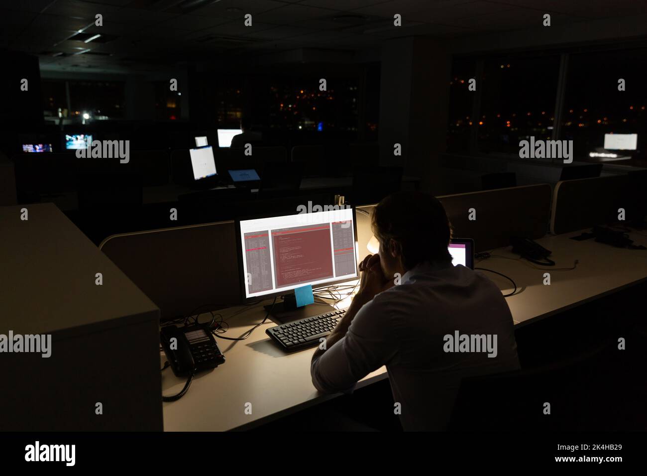 Kaukasischer männlicher Programmierer, der am Schreibtisch sitzt und Computer mit Kodierung auf ...