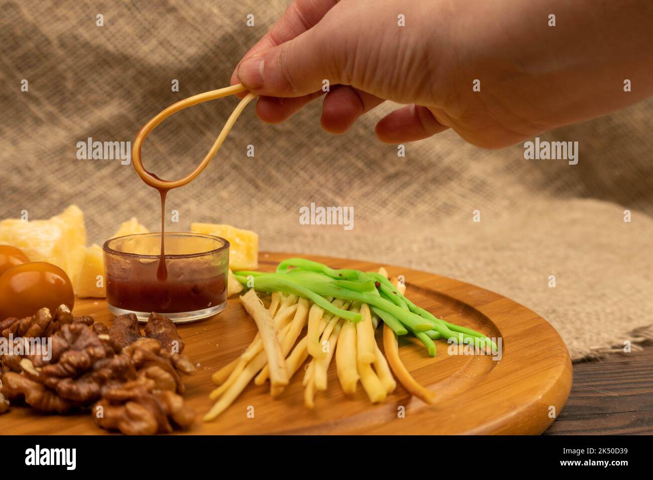 Verschiedene Käsesorten, Walnusskerne, Honig in einer Glasvase und ...