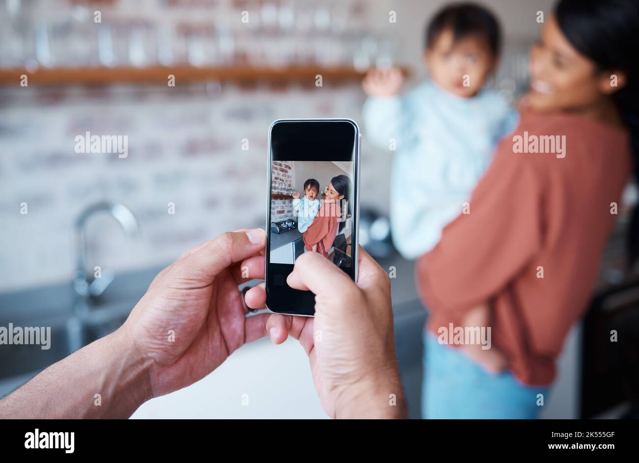 Vater fotografiert Mutter und Baby am Telefon in der Küche ihres ...