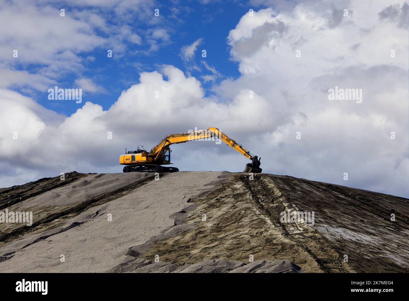 Gelber Raupenbagger auf der Baustelle auf einem großen Erdhaufen mit ...