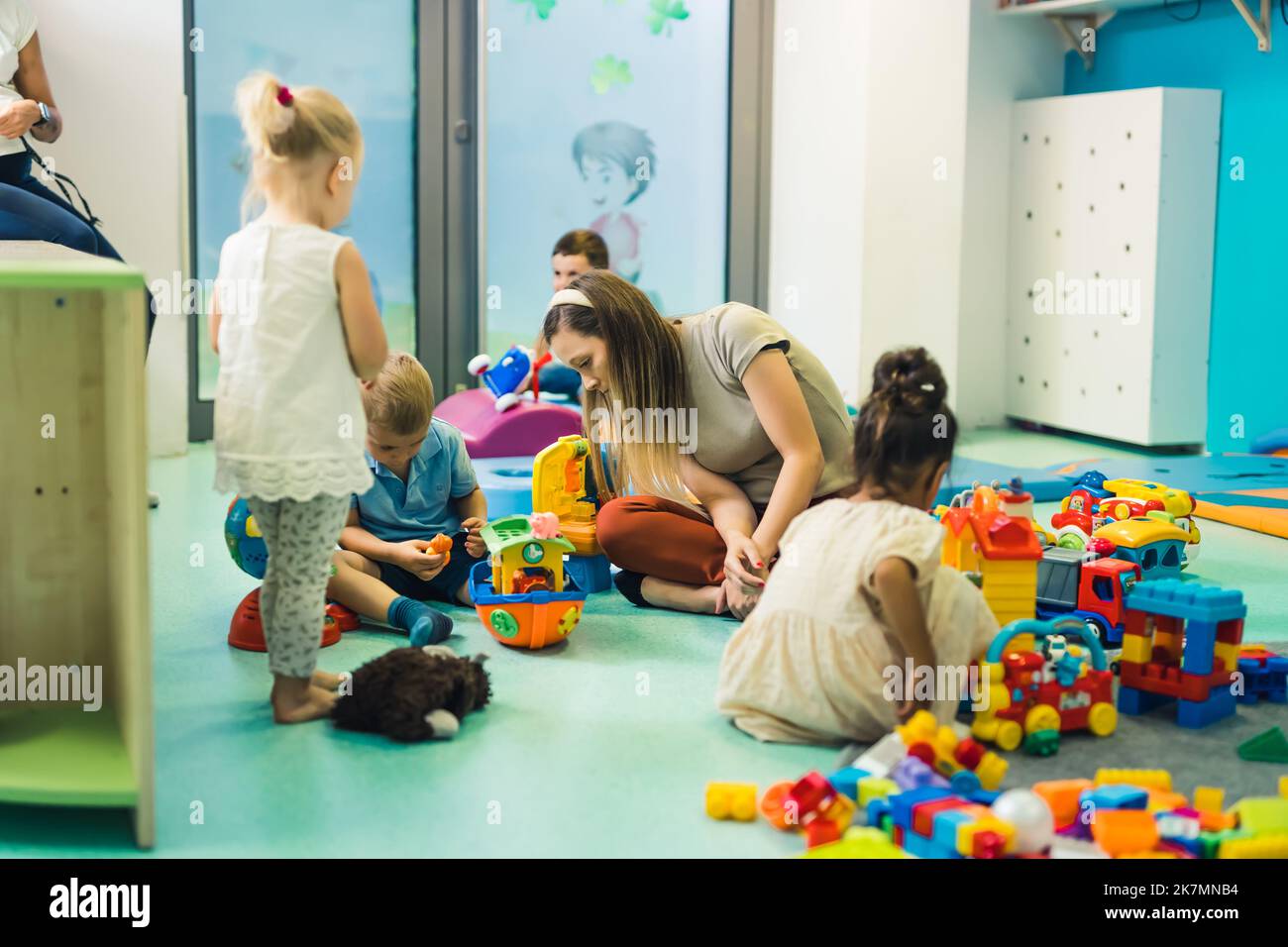 Ein Zimmer im Kindergarten, Kinder, die mit ihrer Lehrerin spielen und Häuser, Schiffe und ...
