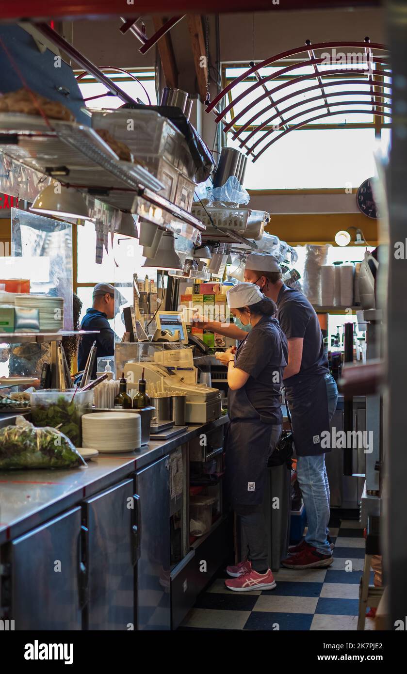 Baristas mit Männern und Frauen, die Schürzen tragen und an einer Theke ...