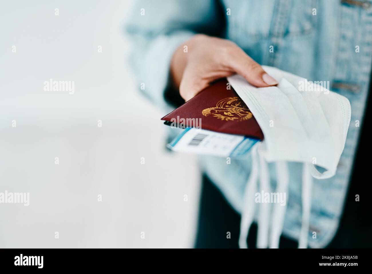 Eine Frau mit Pass, Maske und Bordkarte in einem Flughafen, die einen Covid-19-Reisenden braucht ...
