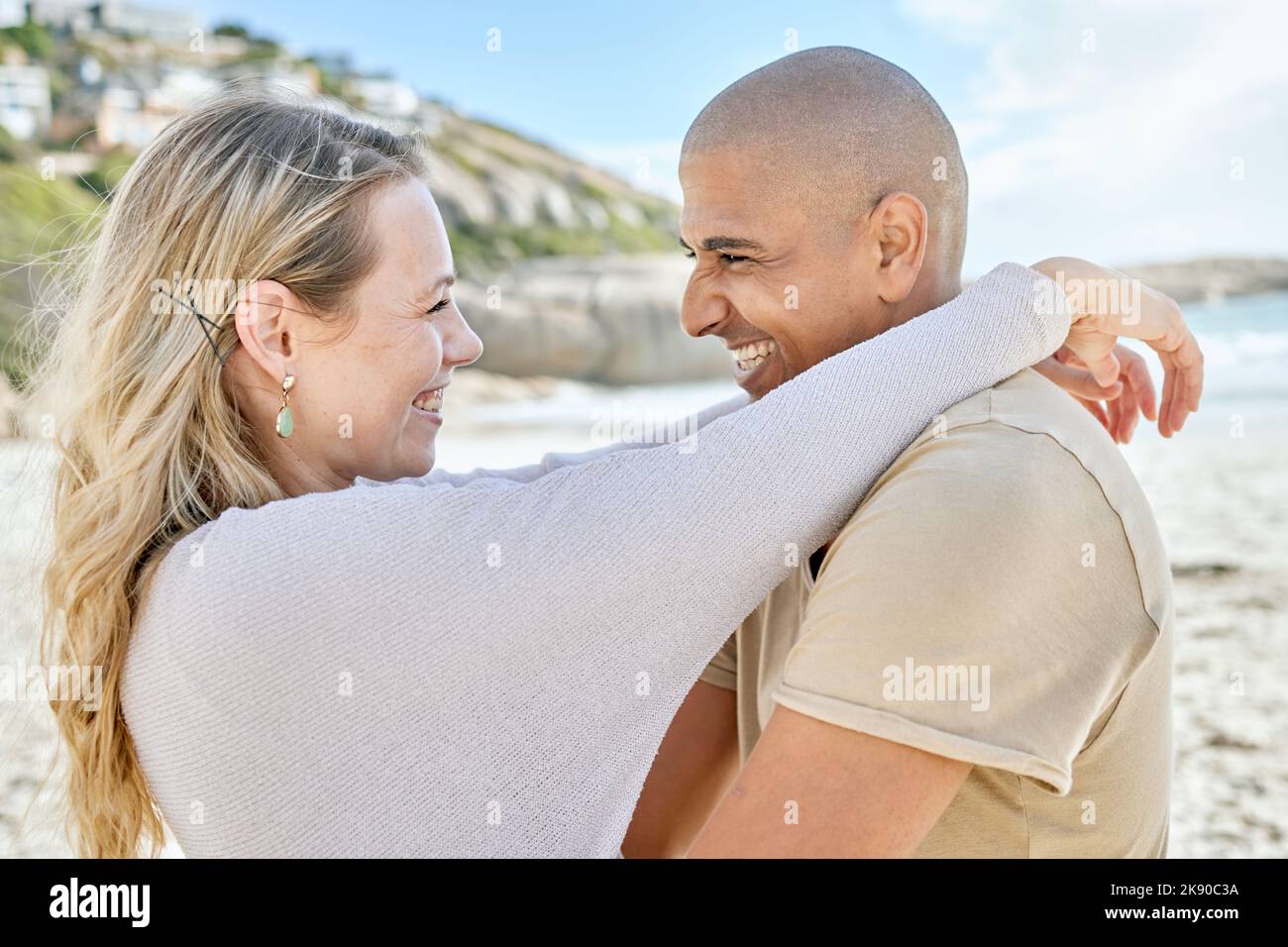 Pärchen, Liebe und Umarmung am Strand lächeln für ein romantisches Date ...
