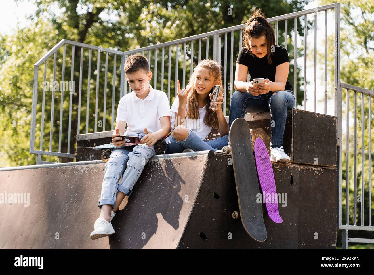 Handy-süchtig Sportkinder mit Skateboard und Penny Boards sitzen und ...