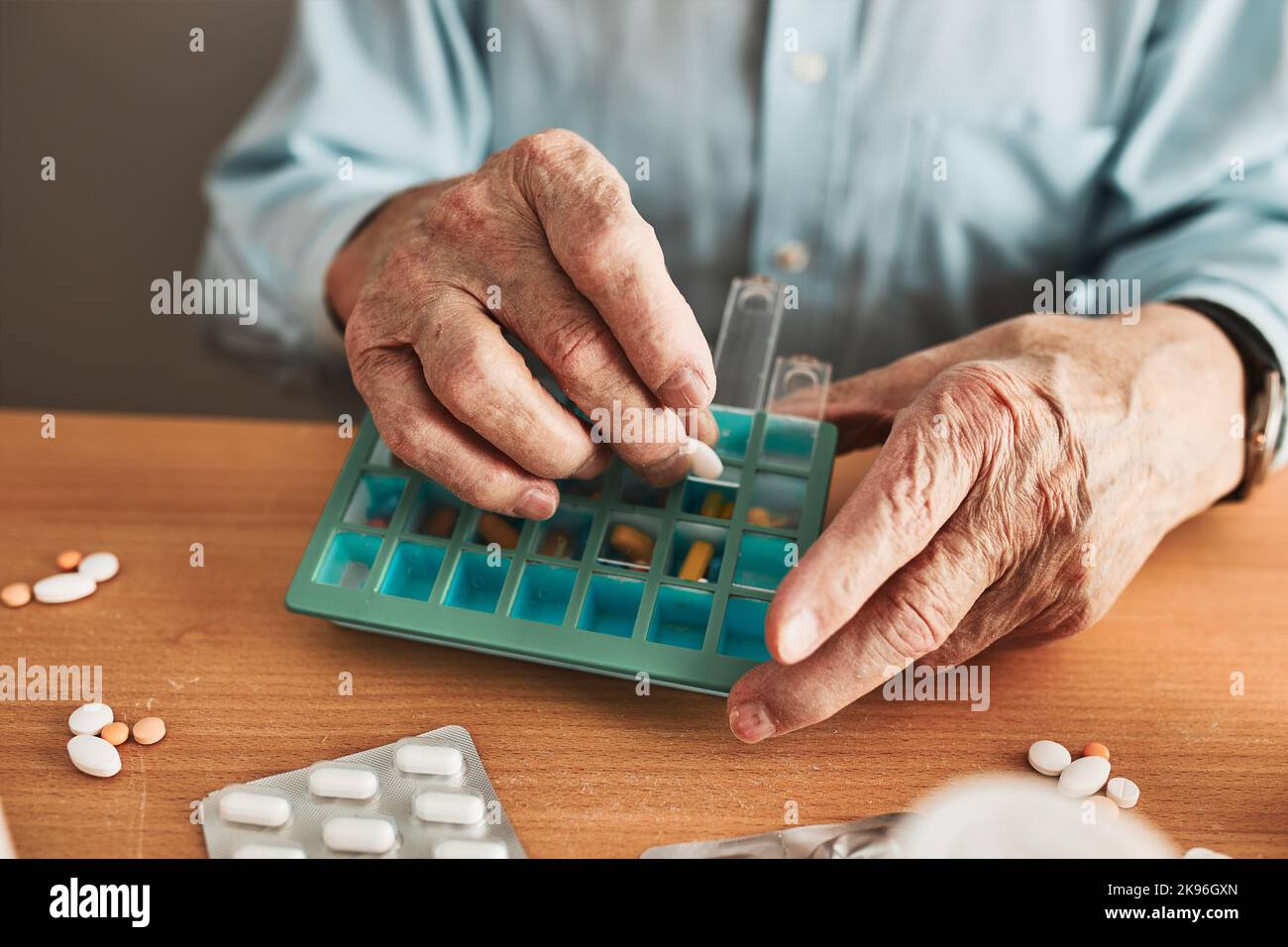 Älterer Mann, der seine Medikamente in einen Pillenspender einsetzte ...
