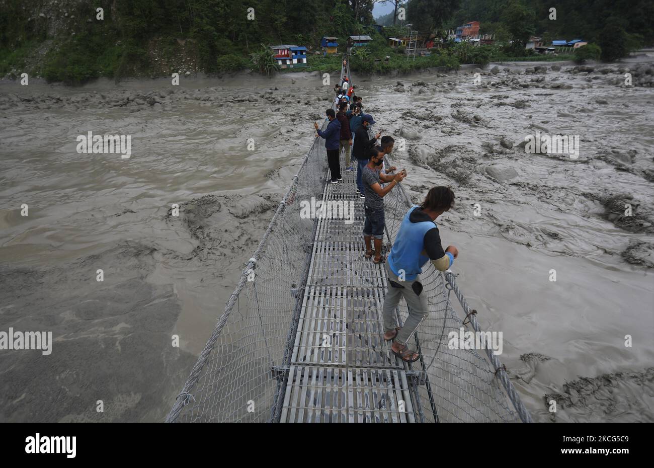 Fußgänger gehen auf einer Hängebrücke über den geschwollenen Melamchi ...