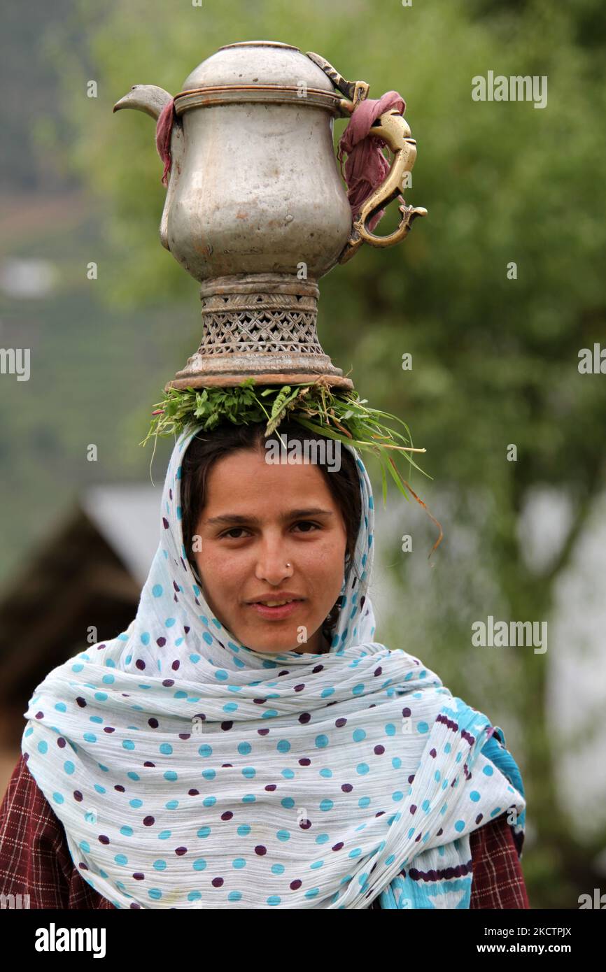 Eine Frau aus Kaschmir trägt einen Samowar auf ihrem Kopf, der mit ...