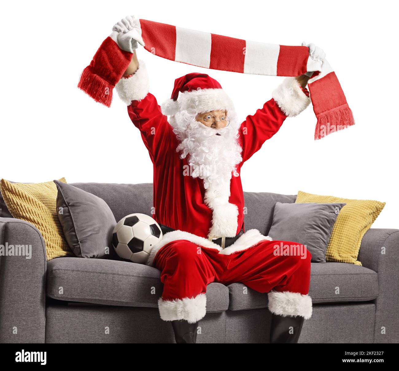 Der aufgeregte weihnachtsmann sitzt mit einem Fußball auf einem Sofa ...