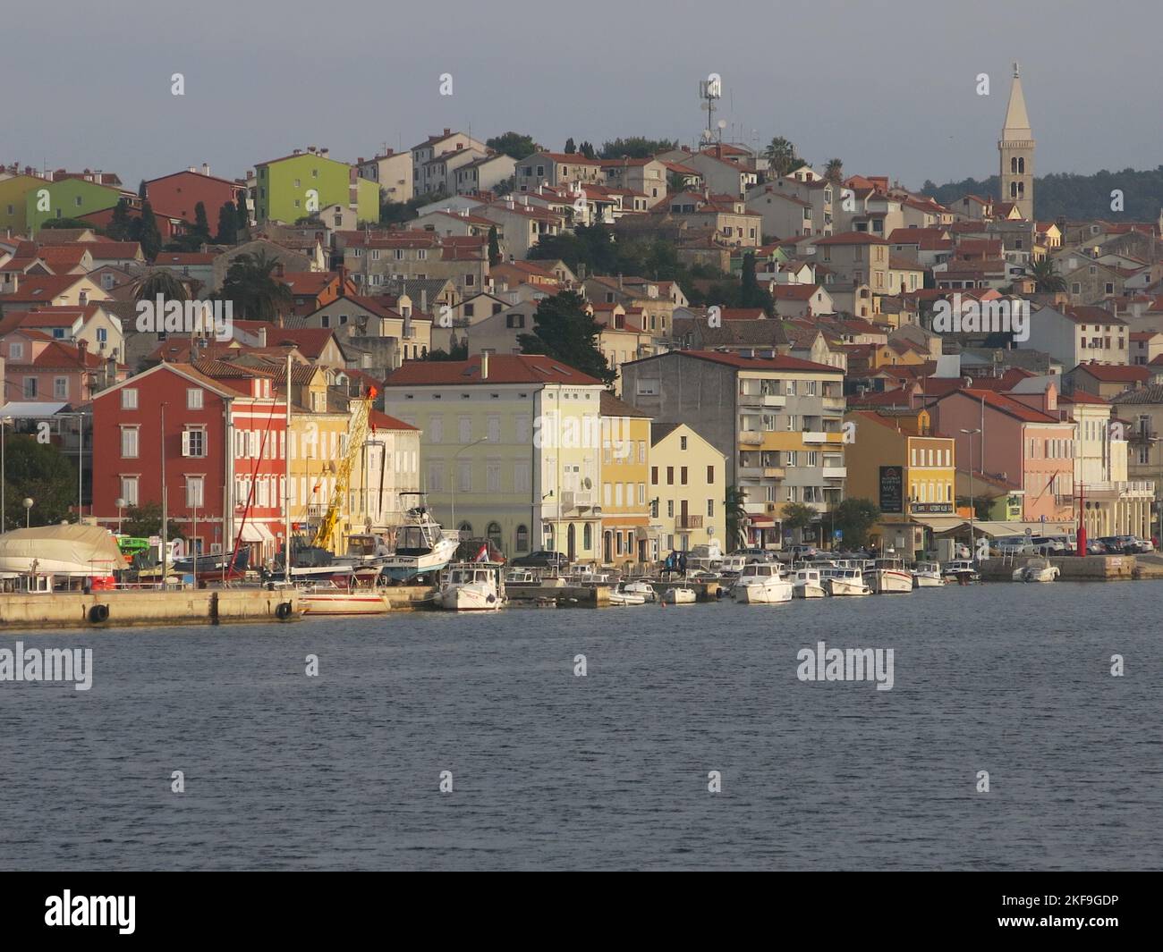 Farbenfrohe mediterrane Stadthäuser säumen die Küste mit Booten, die im ...