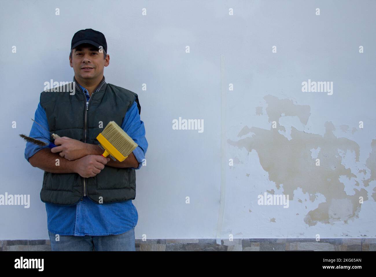 Lächelnder Handwerker, der Pinsel und verschiedene Werkzeuge hält, die ...