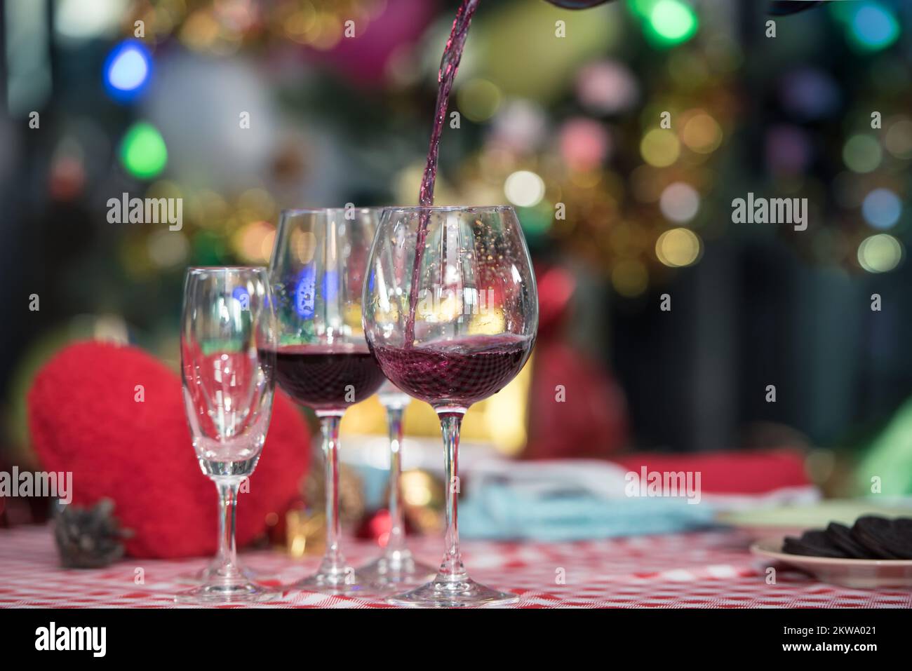 Bei der Weihnachtsfeier schütten Sie Rotwein in Gläser, halten die ...