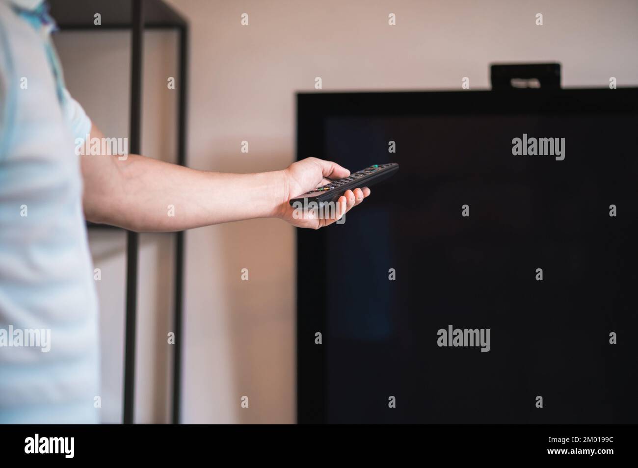 FERNSEHER. Ein Mann in einem Weißen, der zu Hause ist und den fernseher anschaltet ...