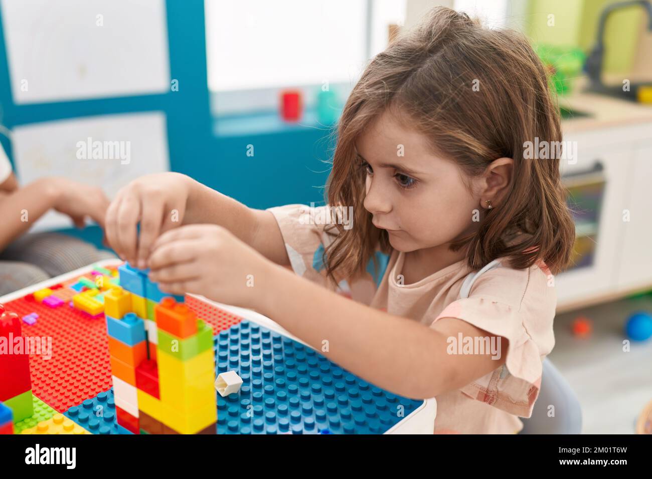 Ein bezauberndes spanisches Mädchen, das mit Bausteinen spielt und im ...