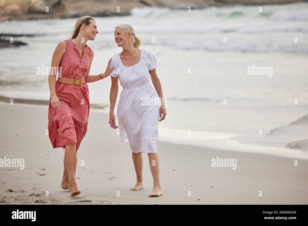 Eine junge kaukasische Frau, die mit ihrer älteren Mutter den Tag am Strand verbringt. Die weiße ...