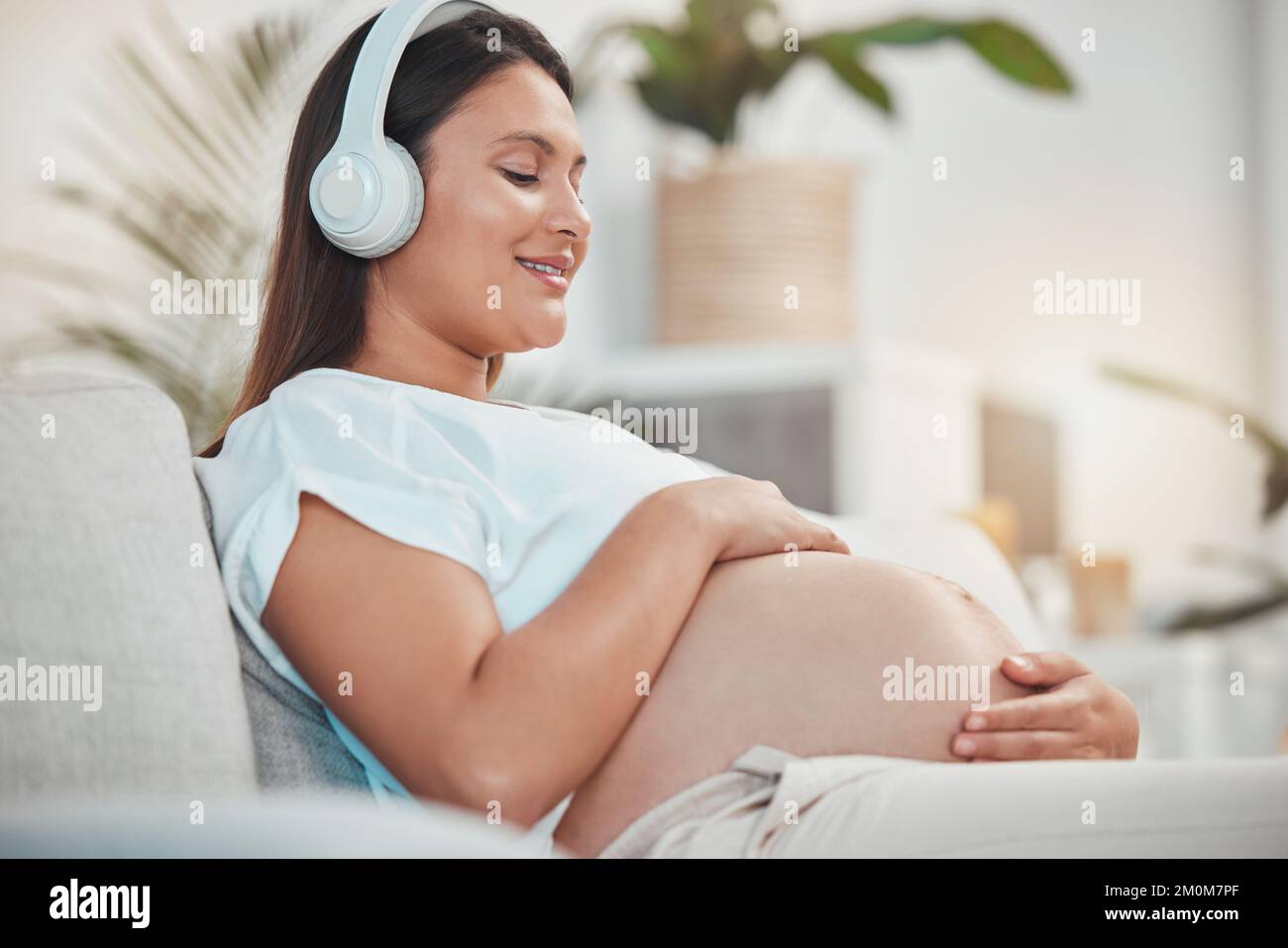 Schwangere Frau, Musik und Bauch oder Beule halten, während sie sich zu ...