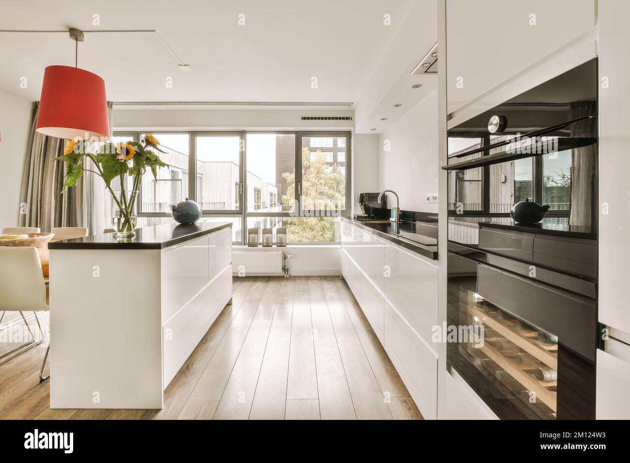 Eine moderne Küche mit Holzfußboden und weißen Schränken in der Mitte ...