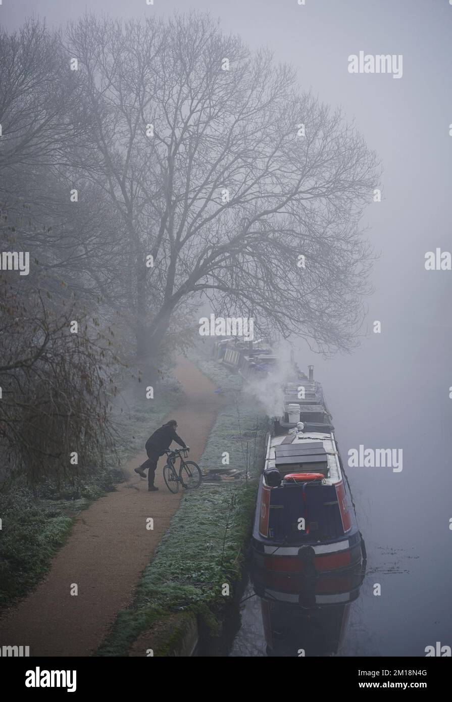 Ein Radfahrer auf einem Pfad am Fluss Lee in Hackney, London. Schnee ...