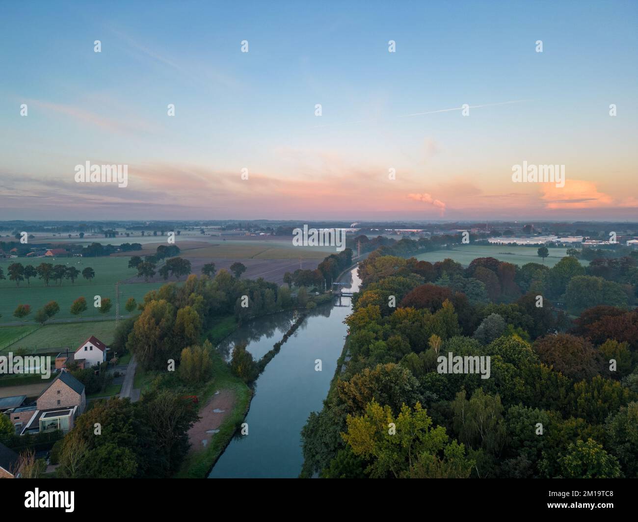 Panorama des dramatischen und bunten Himmels über Feldern, Bäumen und Fluss oder Kanal von einer ...