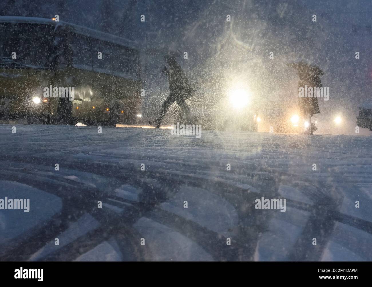 Die Menschen überqueren die Straße inmitten von Schneefall, während ...