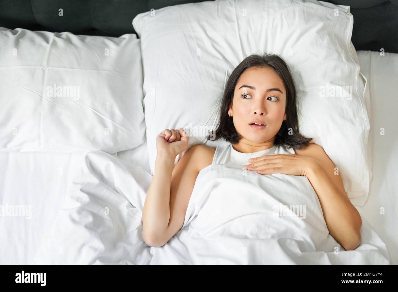 Porträt einer asiatischen Frau, die im Bett lag, schockiert aussah ...