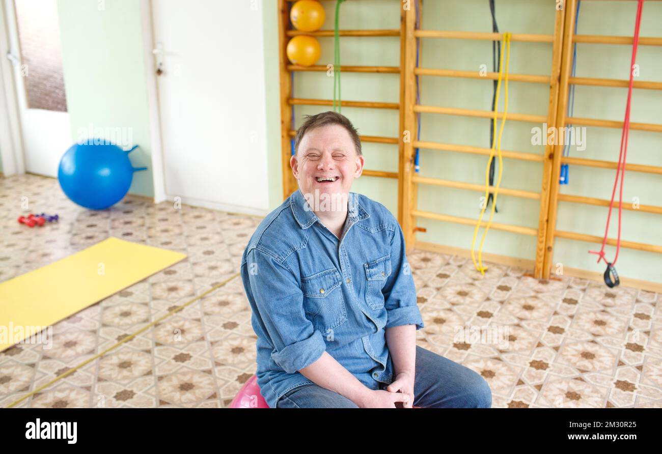 Ein Mann mit Down-Syndrom sitzt auf einem großen aufblasbaren Ball in ...