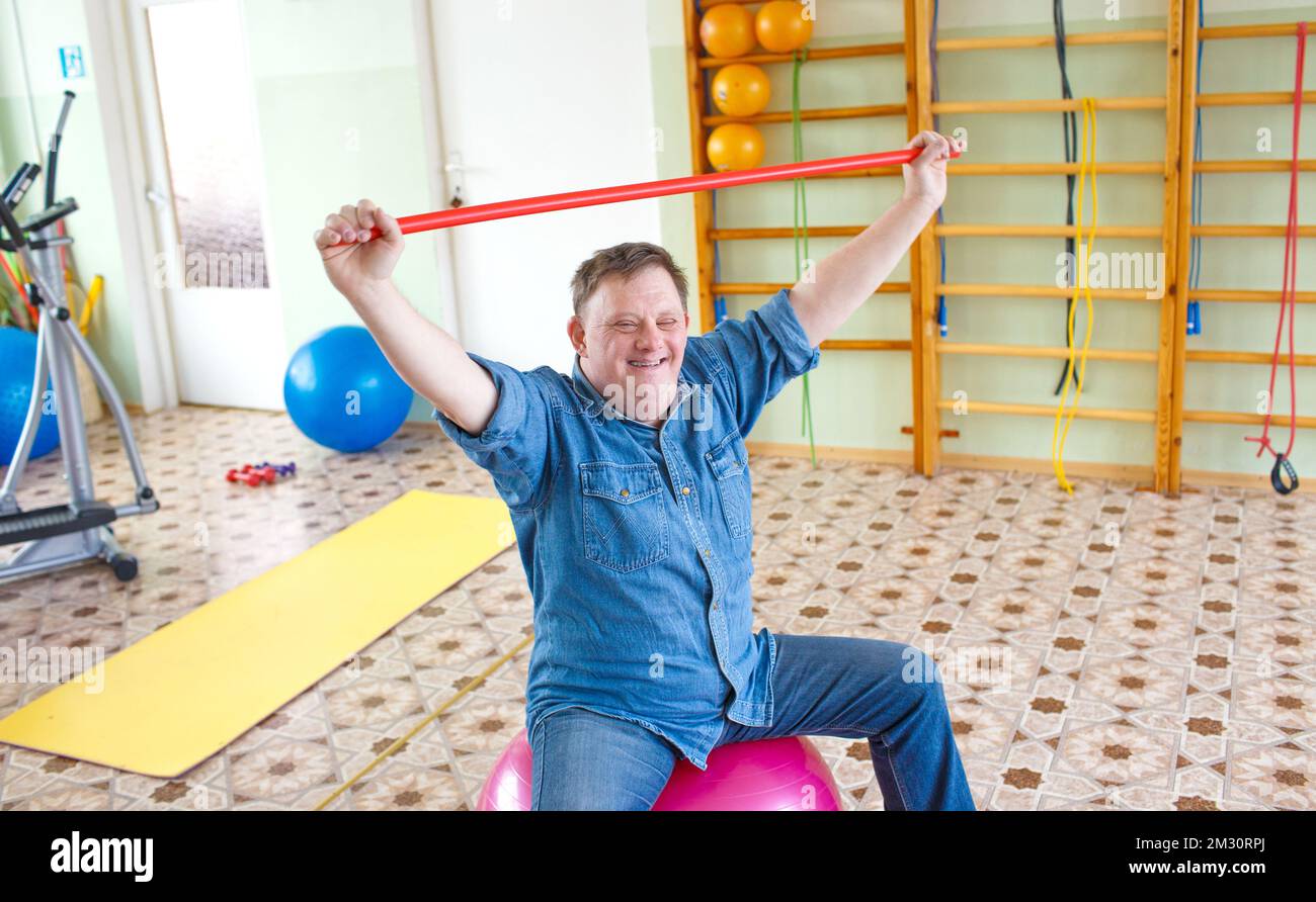 Ein Mann mit Down-Syndrom sitzt auf einem großen aufblasbaren Ball mit ...